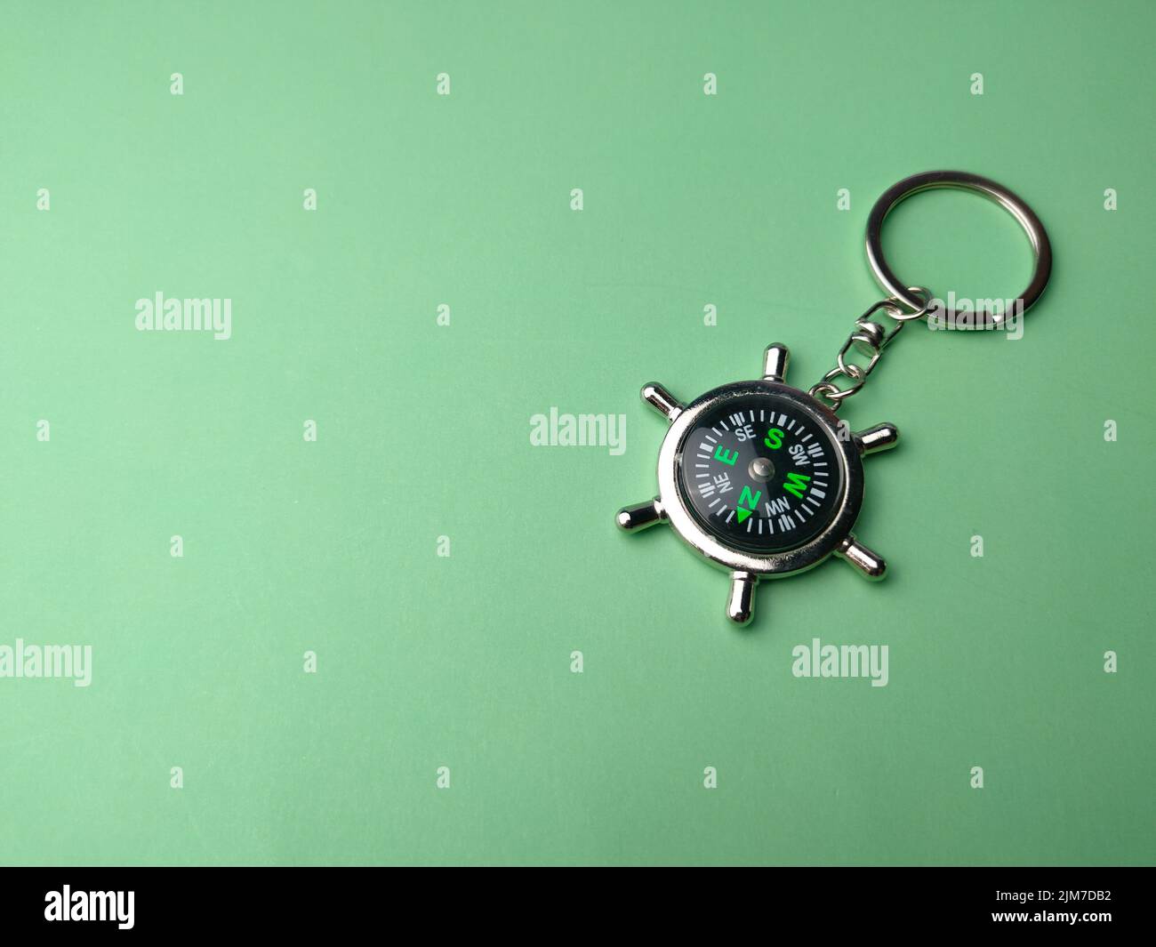 A top view of a compass keychain on a green background with copy space ...