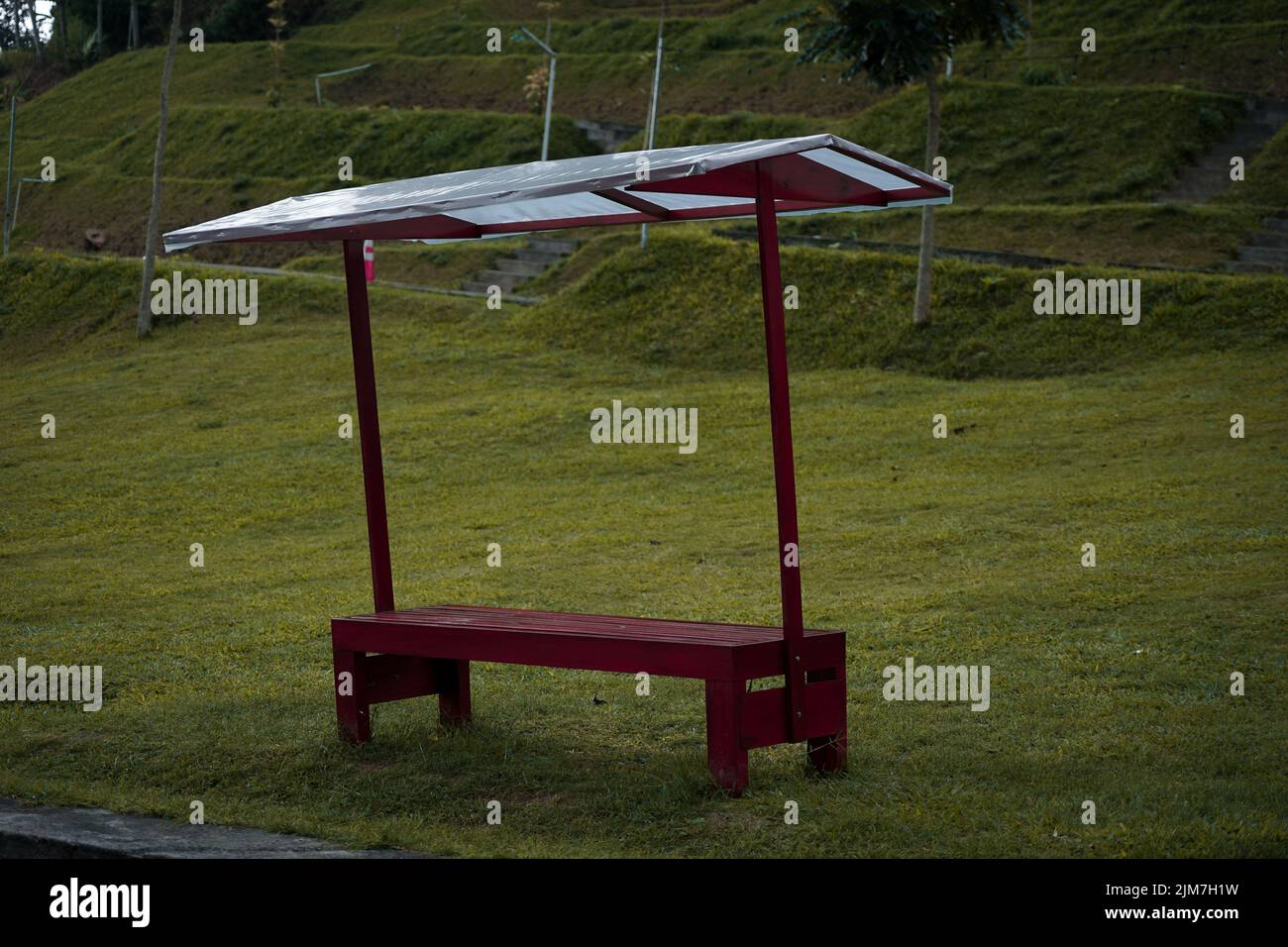 A view of a wooden bench with a roof in the park Stock Photo - Alamy