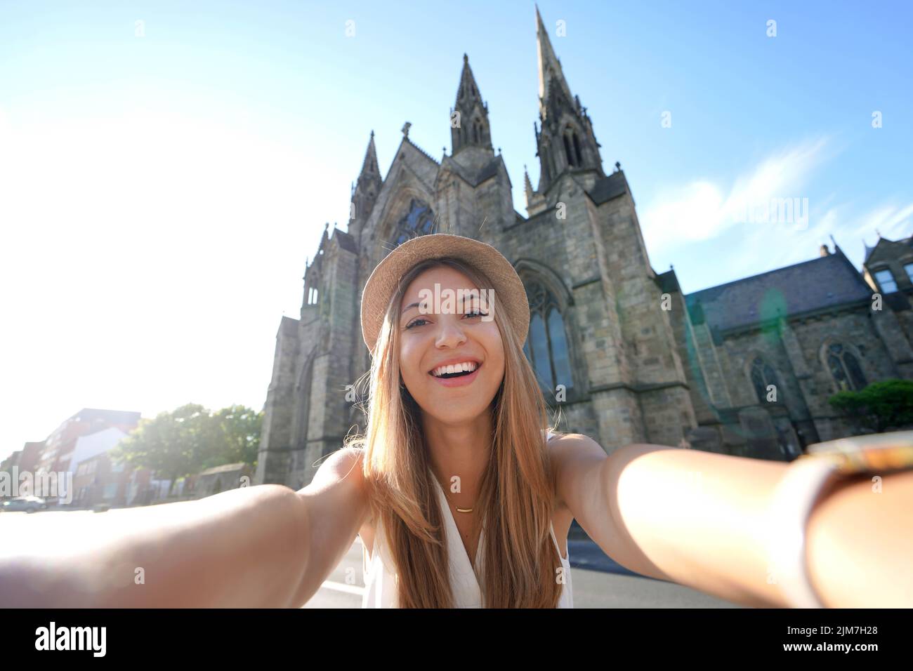Smiling tourist girl takes self portrait in front of Salford Cathedral ...
