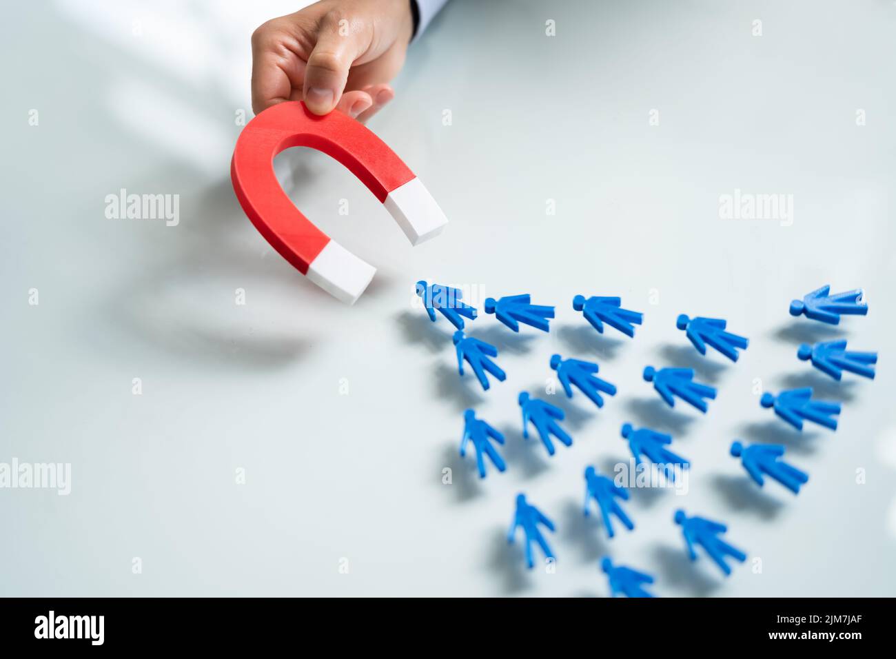 Close-up Of A Human Hand Attracting White Human Figures With Horseshoe ...