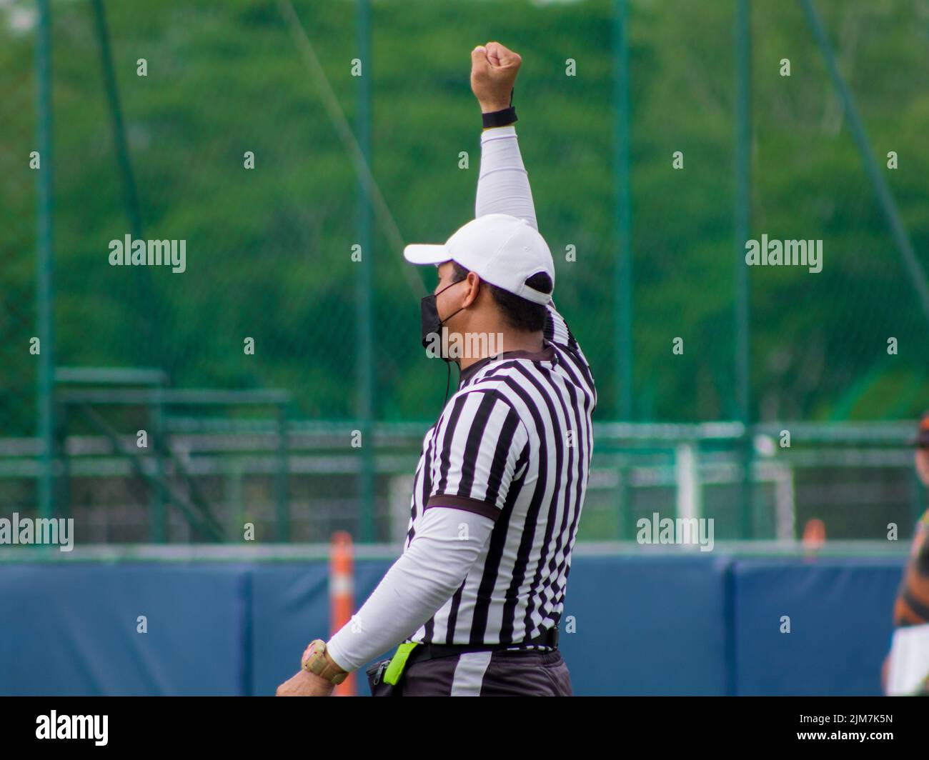 A back shot of a Male referee doing a fist sign during a Flag football ...
