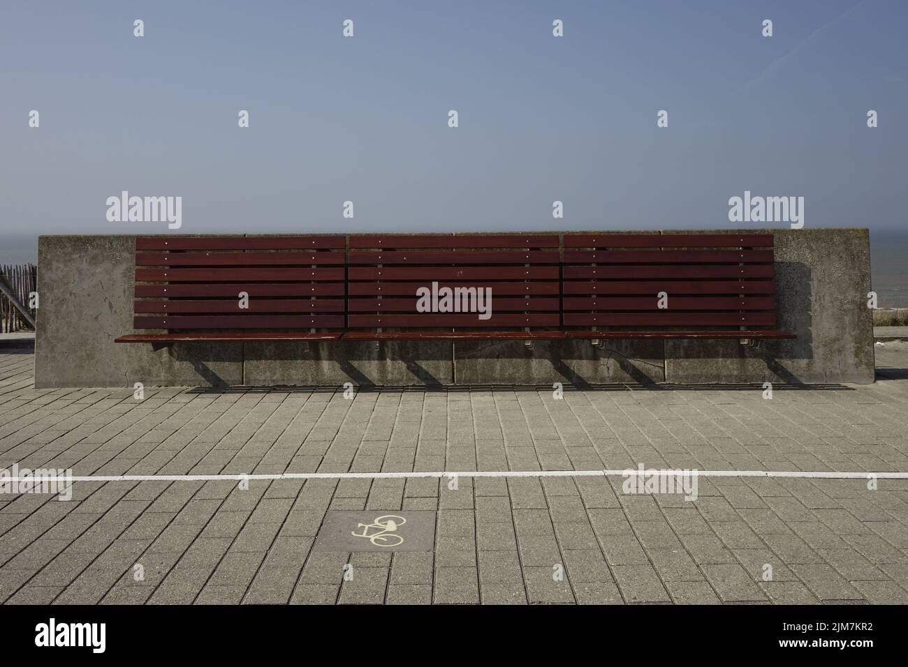 Red wooden seat bench at a concrete wall in the North Sea dunes ...