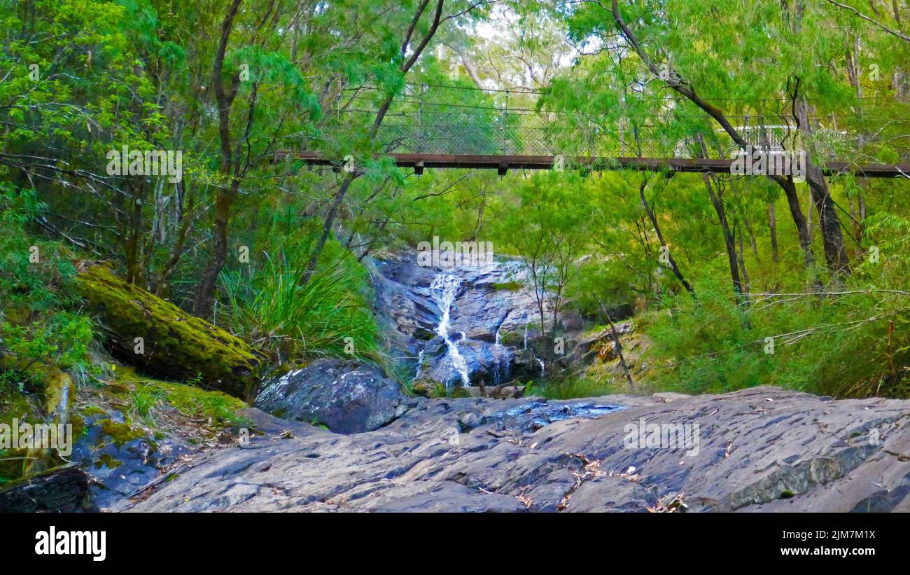 Wooden foot bridge above a stream flowing over granite boulders Stock ...