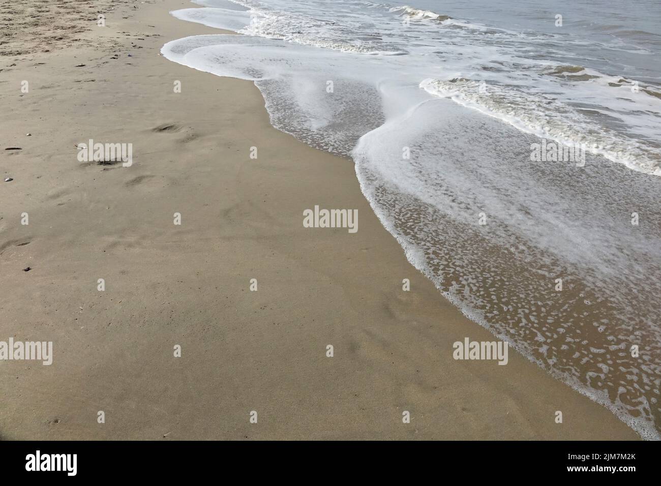 Foam of ocean waves rolling on Dutch North Sea beach (horizontal ...