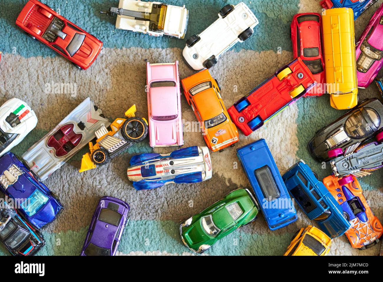 A collection of many Mattel Hot Wheels toy model cars on a carpet floor ...