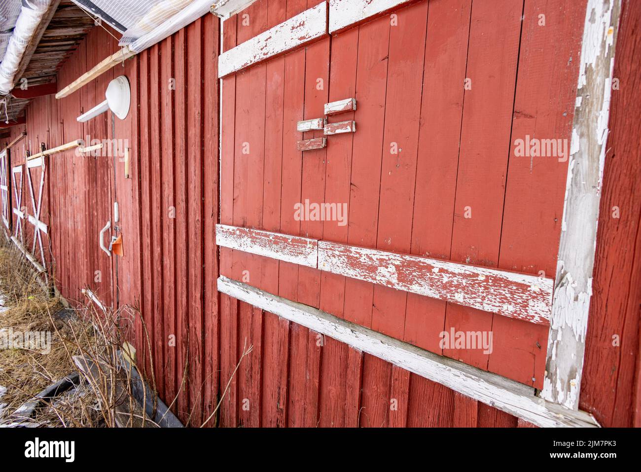 A closeup of a red painted wooden door in a farmhouse with white frames ...