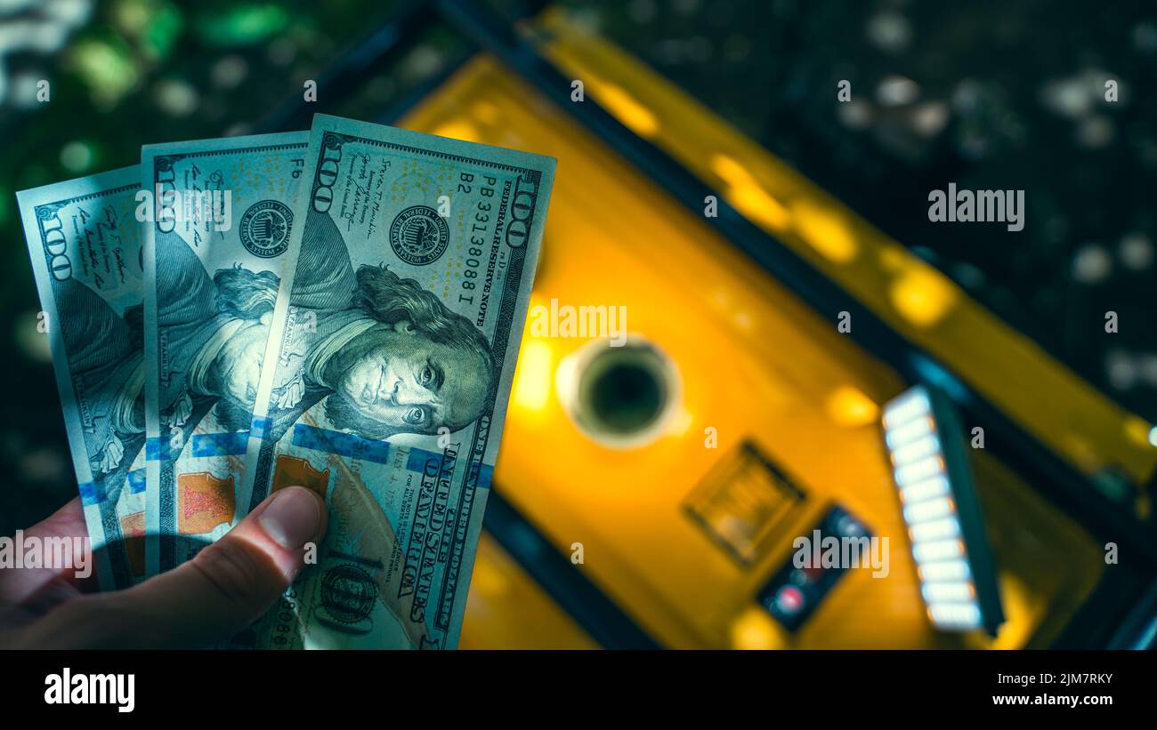 Three one hundred dollar bills in a hand close-up against the ...