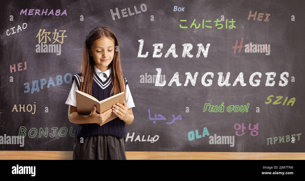 Schoolgirl reading a book and standing in front of a blackboard with ...