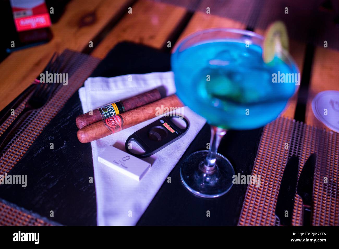 Closeup photo of many cigars on the table with a blue cocktail Stock ...
