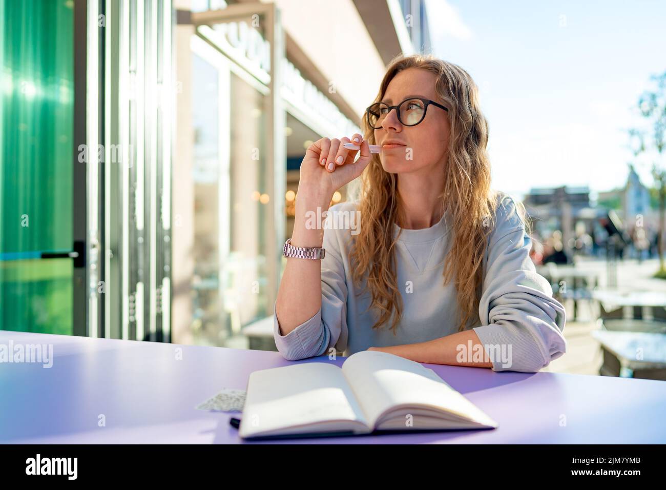Casual woman sitting at table and taking notes in notebook .on the cafe ...