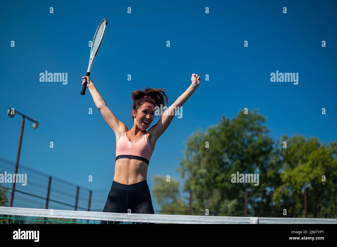 The female winner celebrates her tennis success. The happy girl is ...
