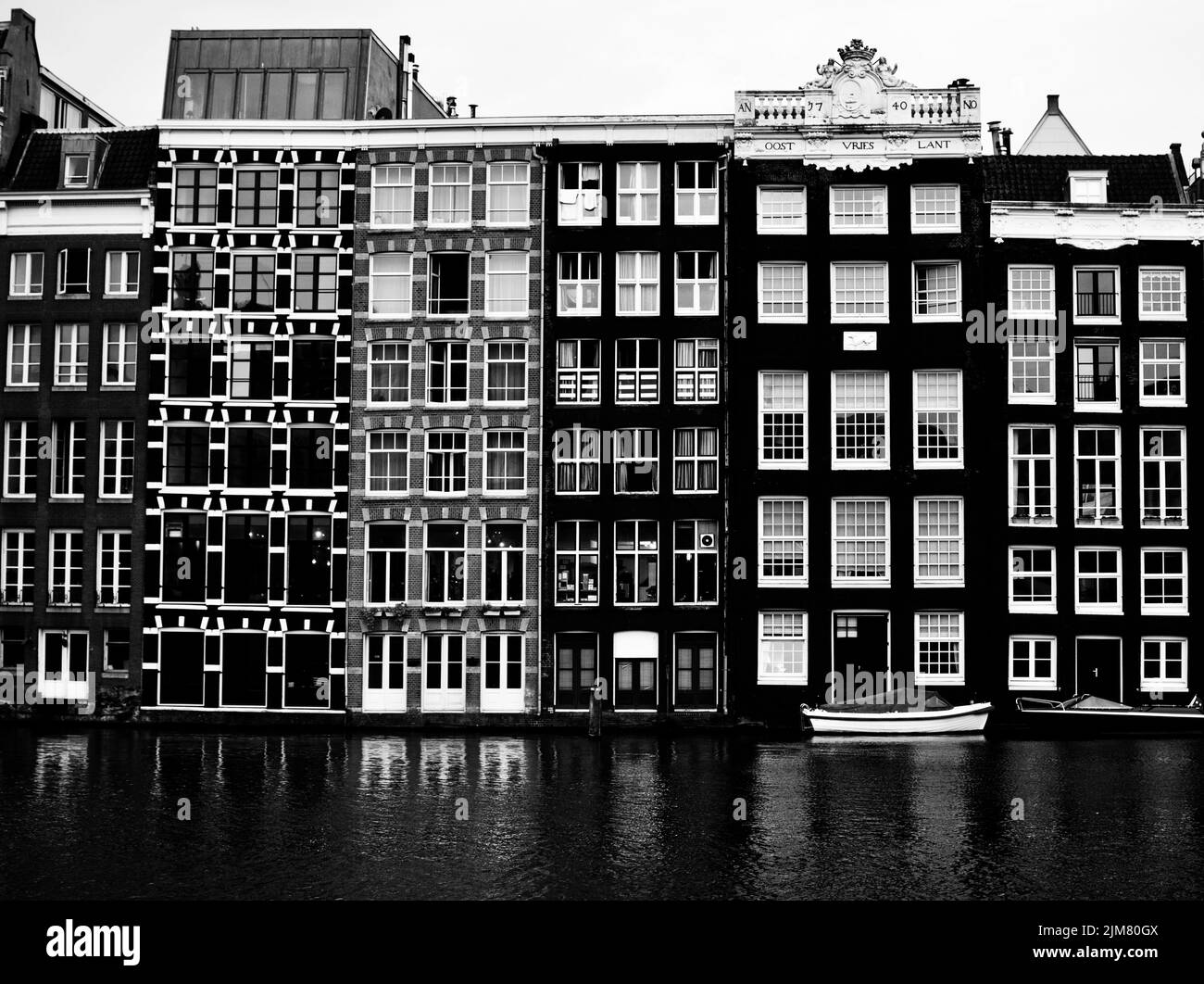 A grayscale of modern buildings by the lake with a boat Stock Photo - Alamy