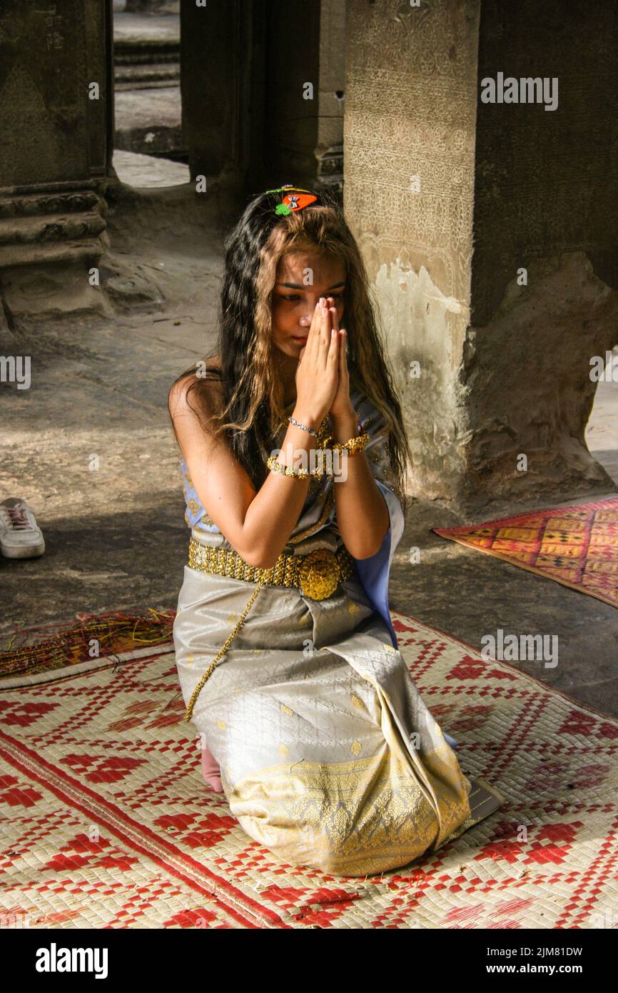 Cambodian woman in traditional clothing praying at Angkor Wat, Angkor ...