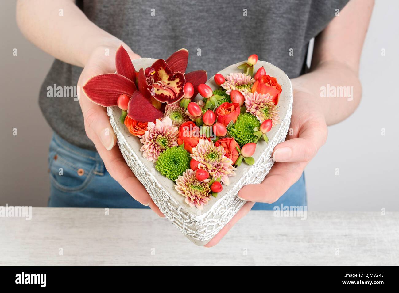 Woman holding small floral arrangement in heart shape. Party time Stock ...