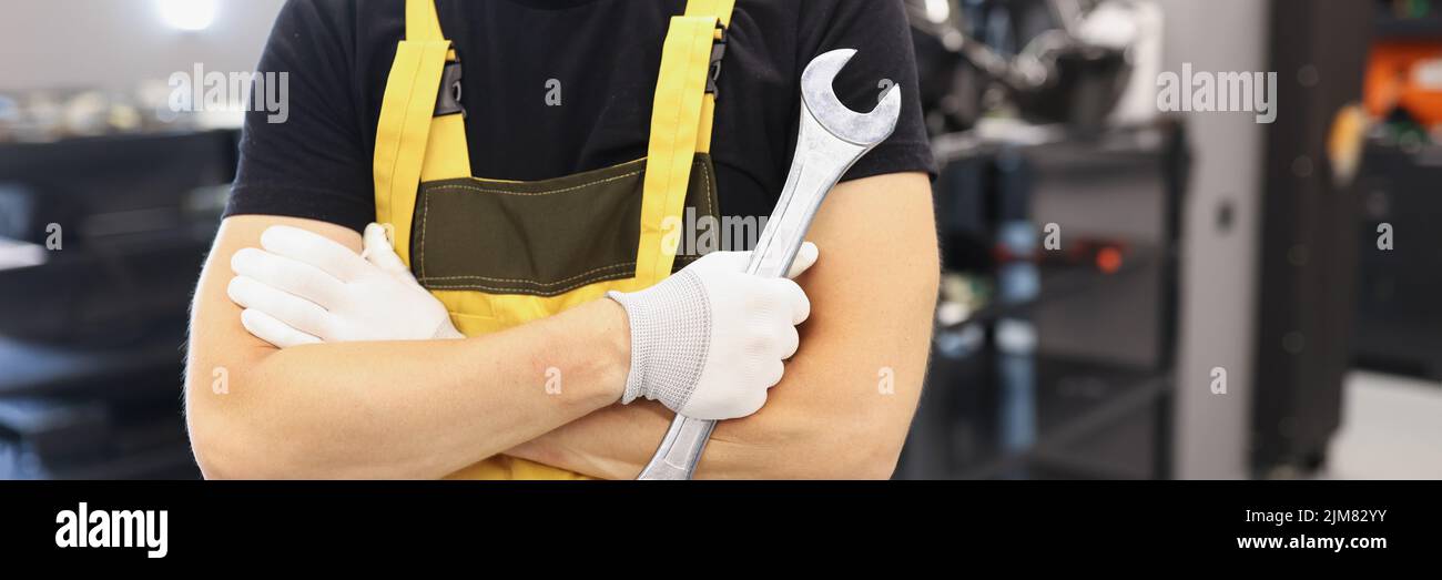 Strong man in yellow overalls holding a wrench Stock Photo - Alamy