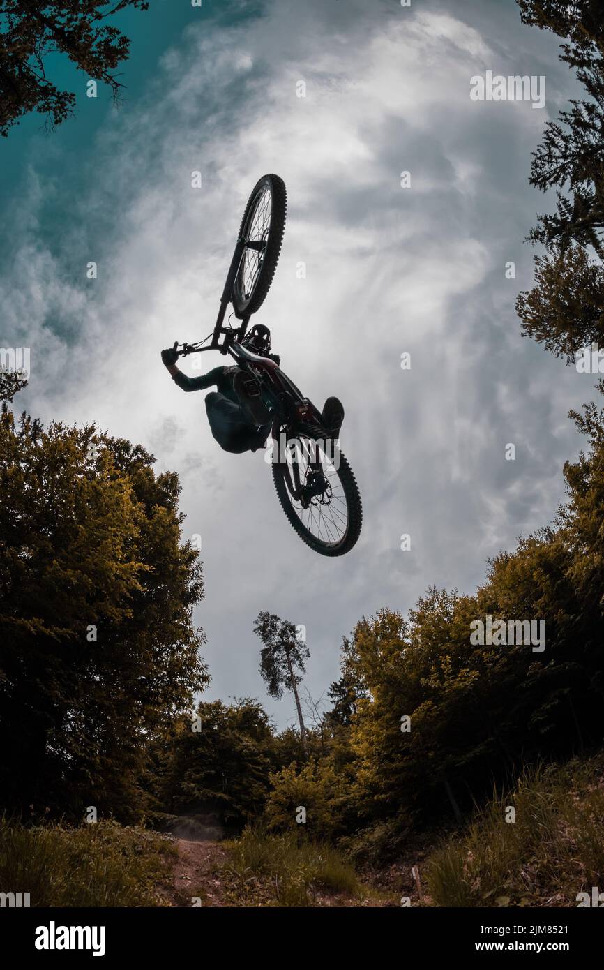 Silhouette of a mountain biker jumping over camera and performing tail ...