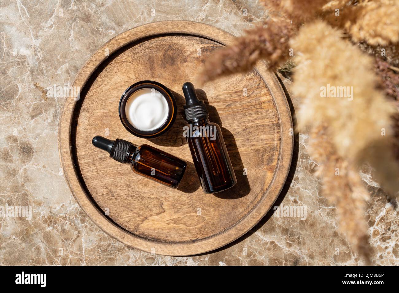 Set of amber glass cosmetic bottles on wooden tray. dropper bottle and ...