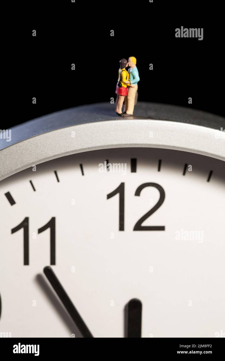 Miniature pair hugs each other standing on a clock Stock Photo - Alamy