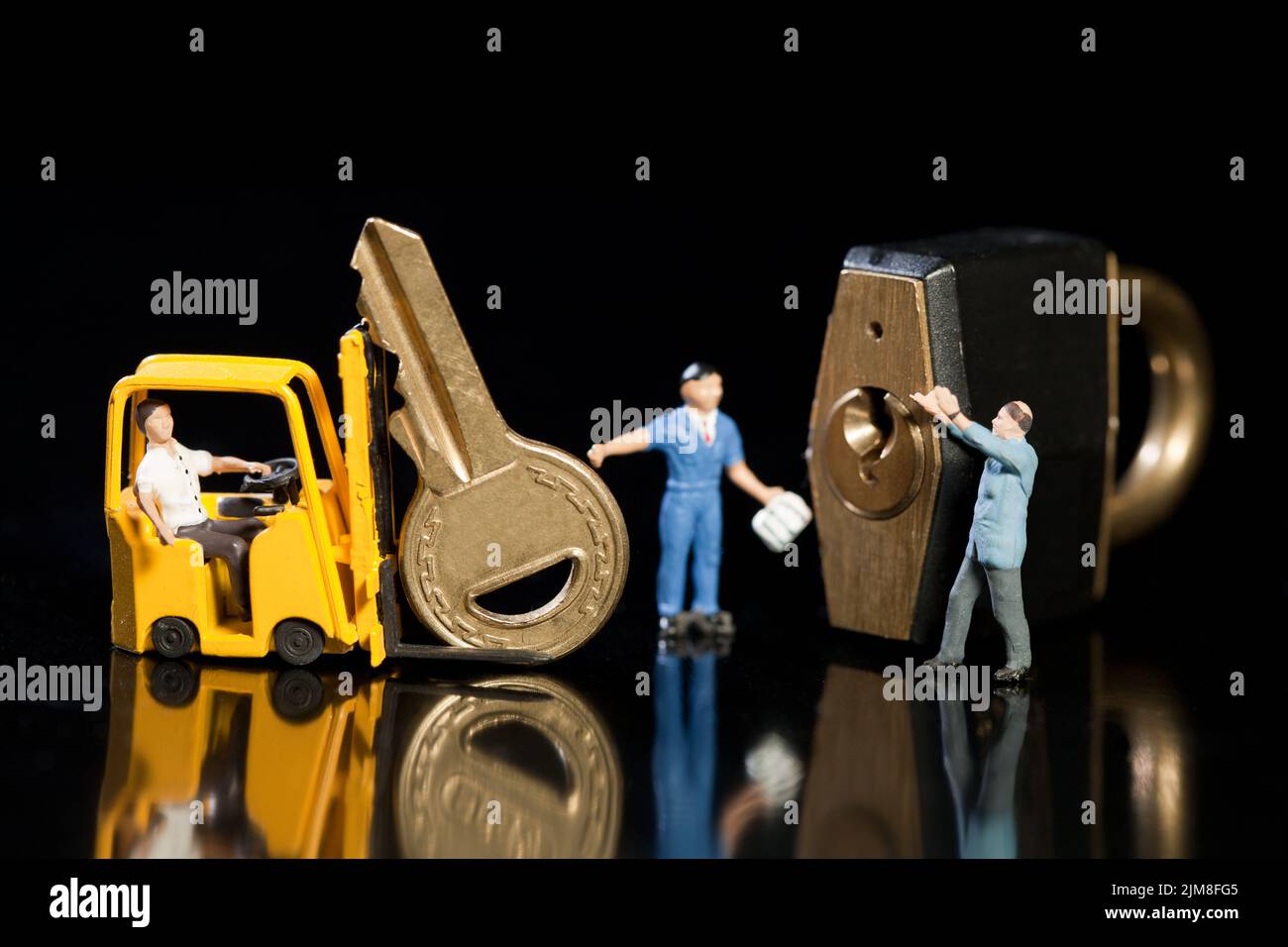 Miniature workers lock a padlock together Stock Photo - Alamy