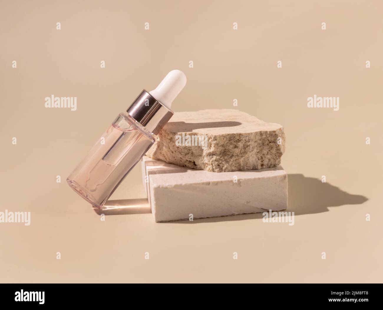 Glass cosmetic dropper bottle on beige travertine stones on light ...