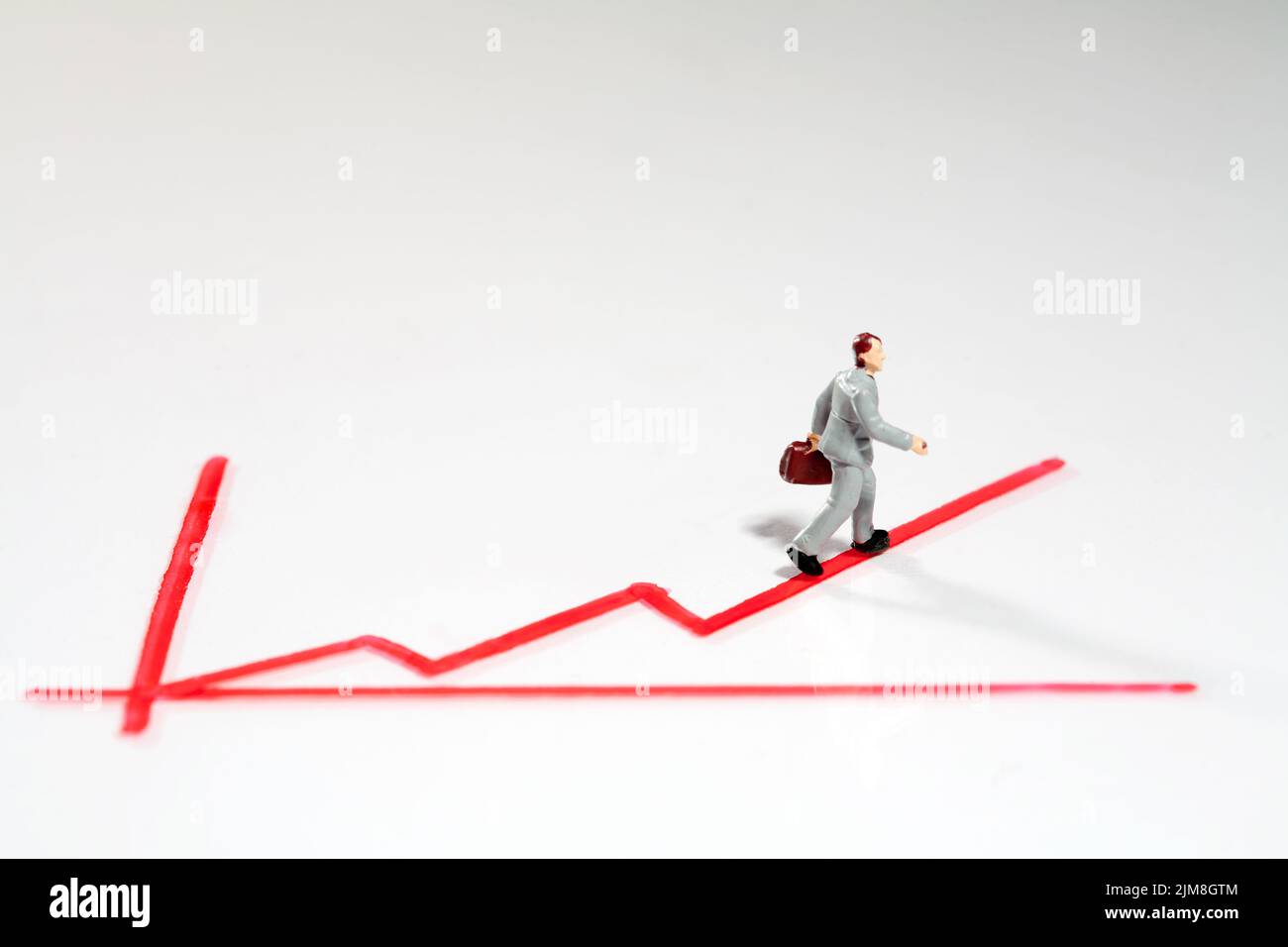 Mini figure follows ascending graph Stock Photo - Alamy