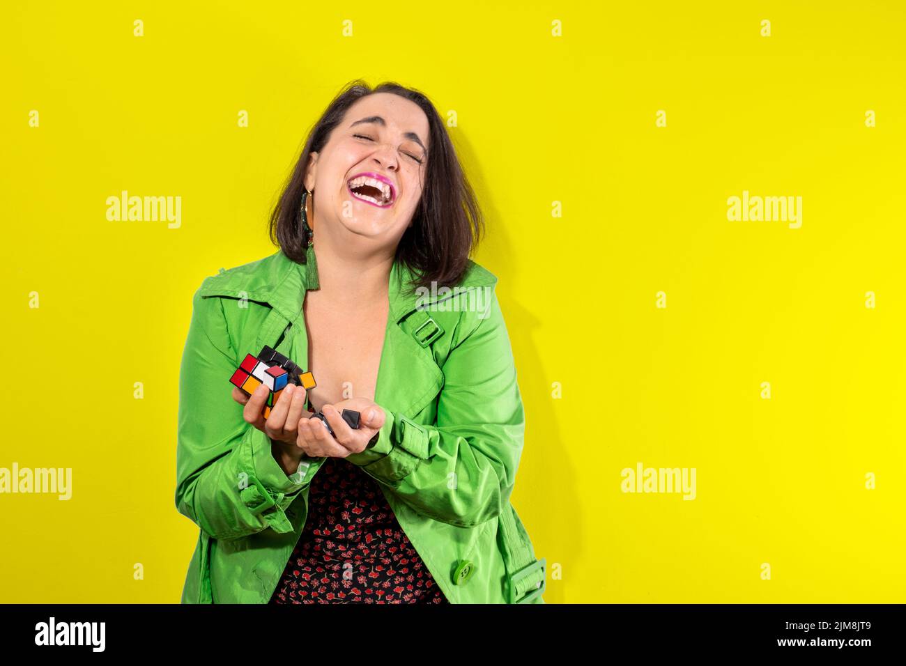 girl laughing after breaking the rubik's cube. yellow background Stock ...