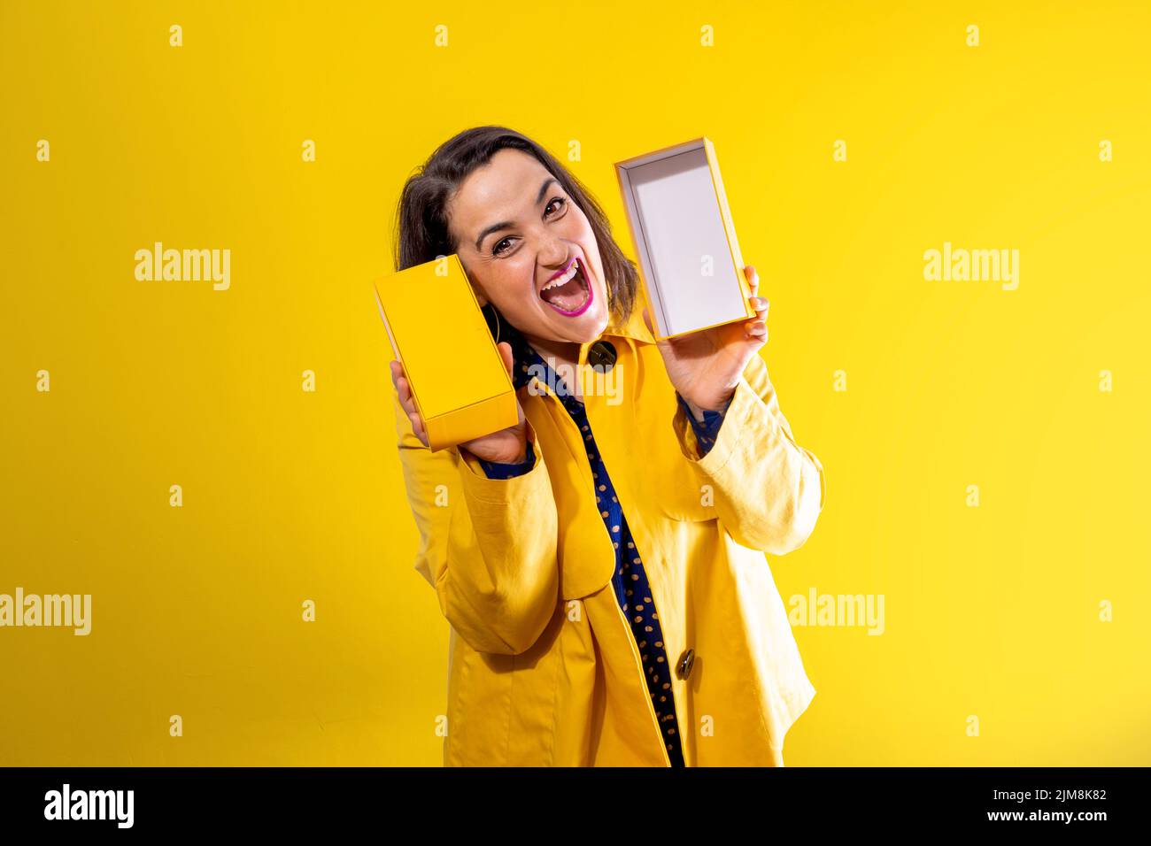 young girl on yellow background uncovering a box Stock Photo - Alamy