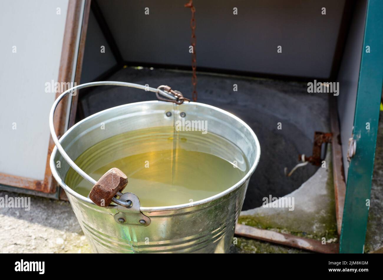 Metal bucket at draw-well in European village. Retro stone water well ...