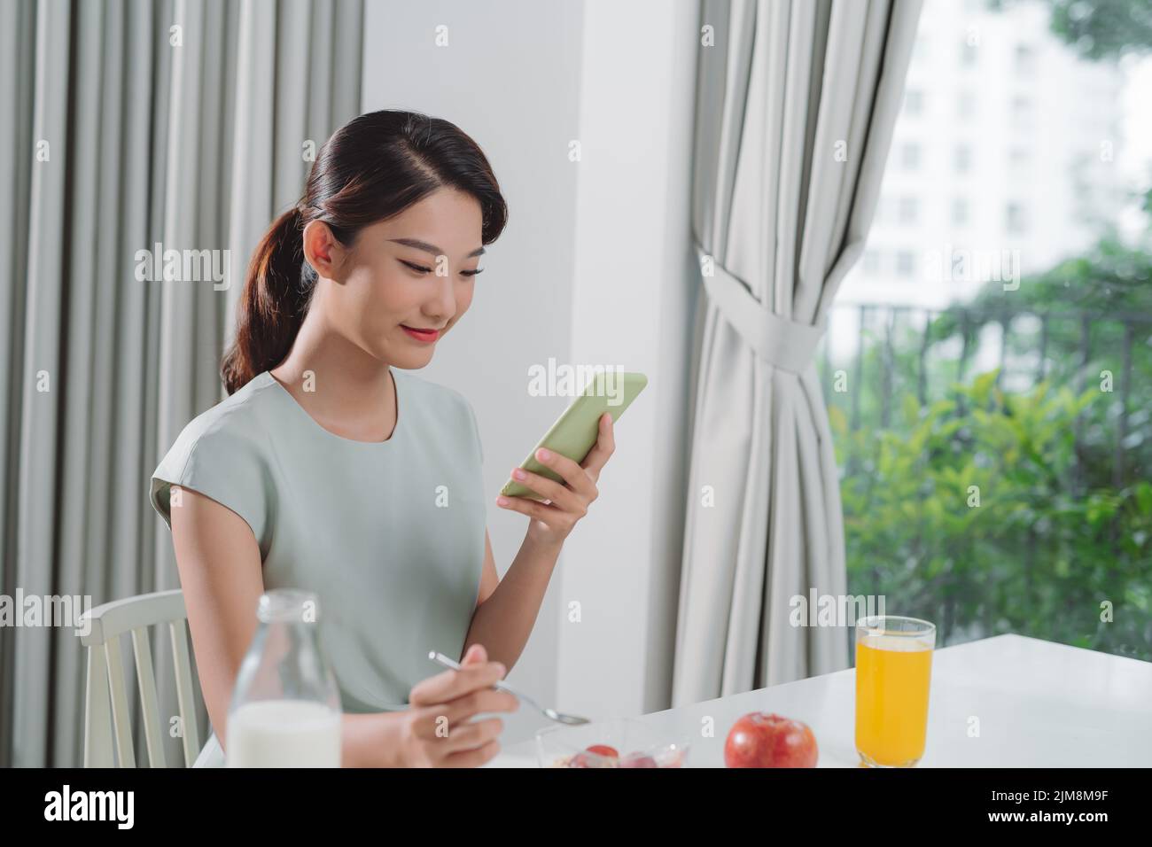 a asian woman eating and being distracted by social media Stock Photo ...