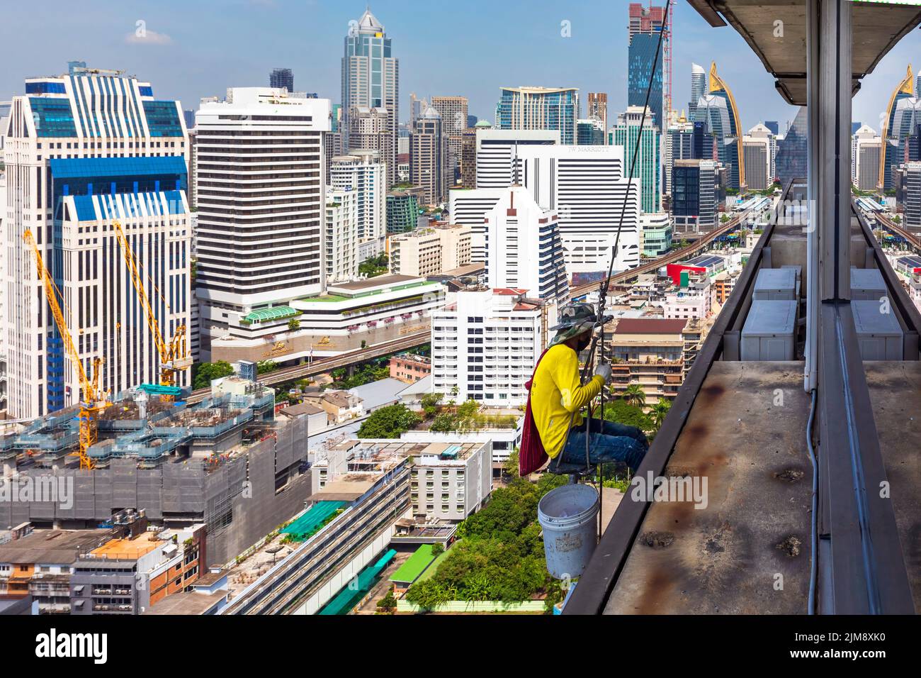 Thai workman repairing window in high rise building using rope and ...