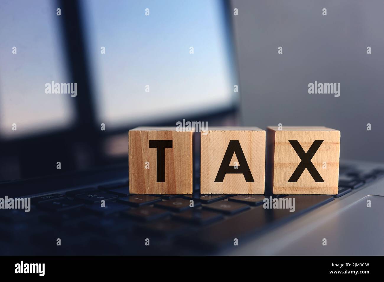 The laptop screen on the table is open. Tax word on wooden cubes on ...