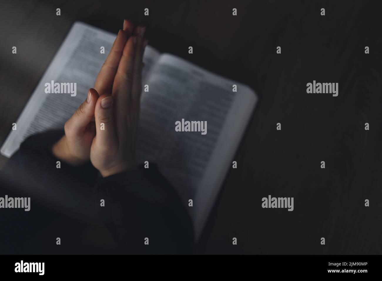 Woman hands on Bible. she is reading and praying over bible in a dark ...
