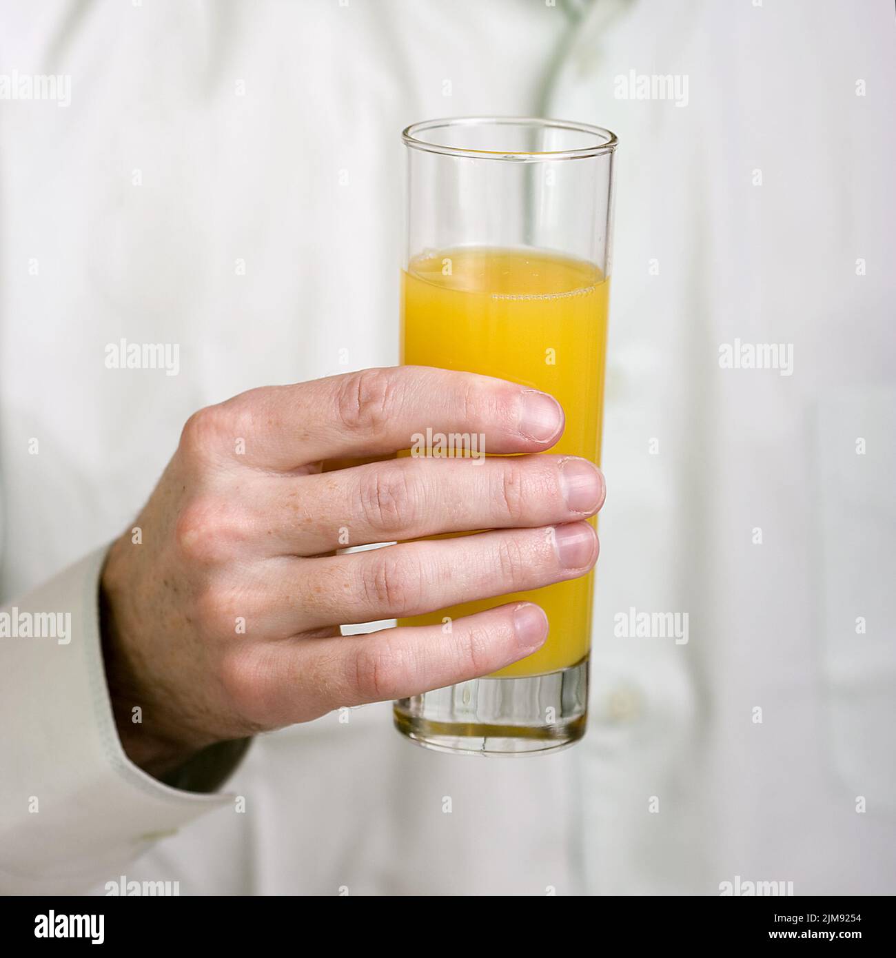 Glass with orange juice in a hand Stock Photo - Alamy