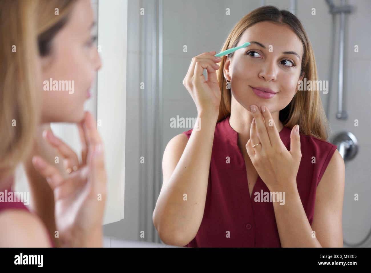 Brazilian woman shaving her eyebrows by razor at home. Pretty woman ...
