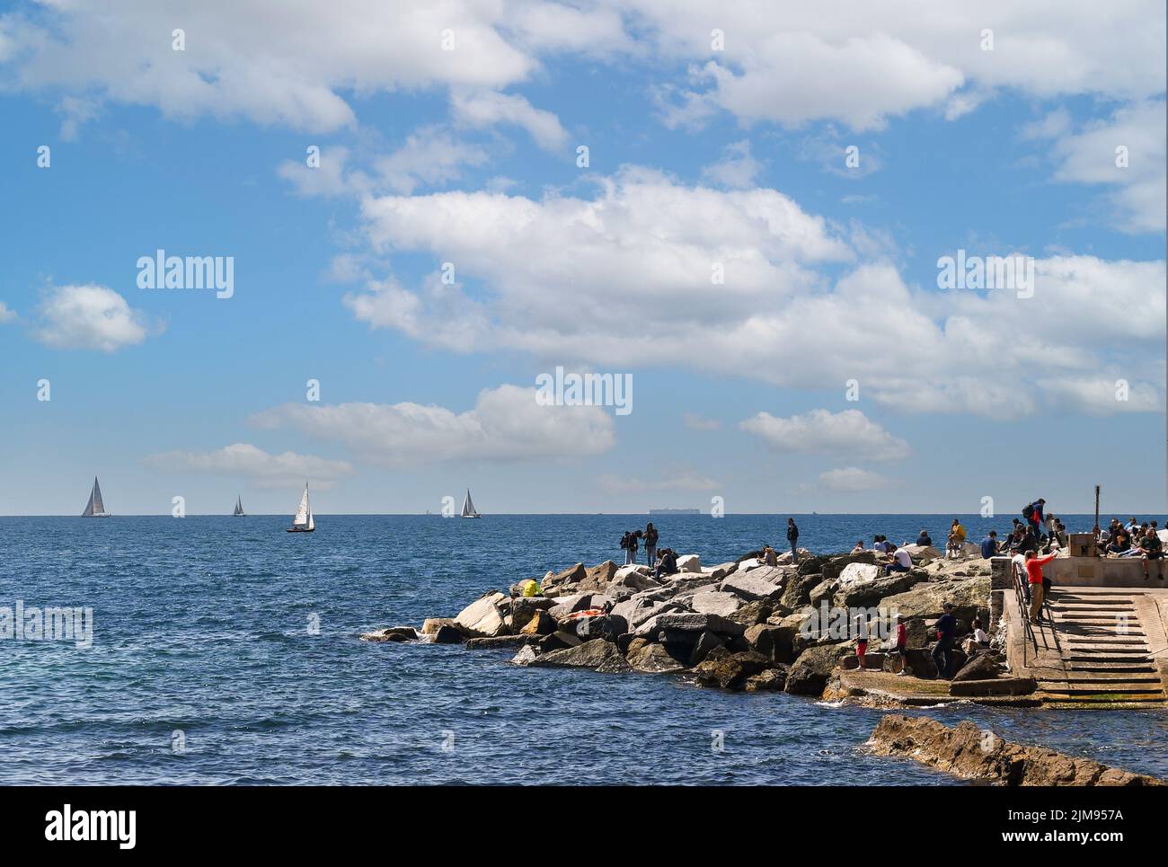 Tourists on the rocky breakwater on the seashore of the fishing village ...