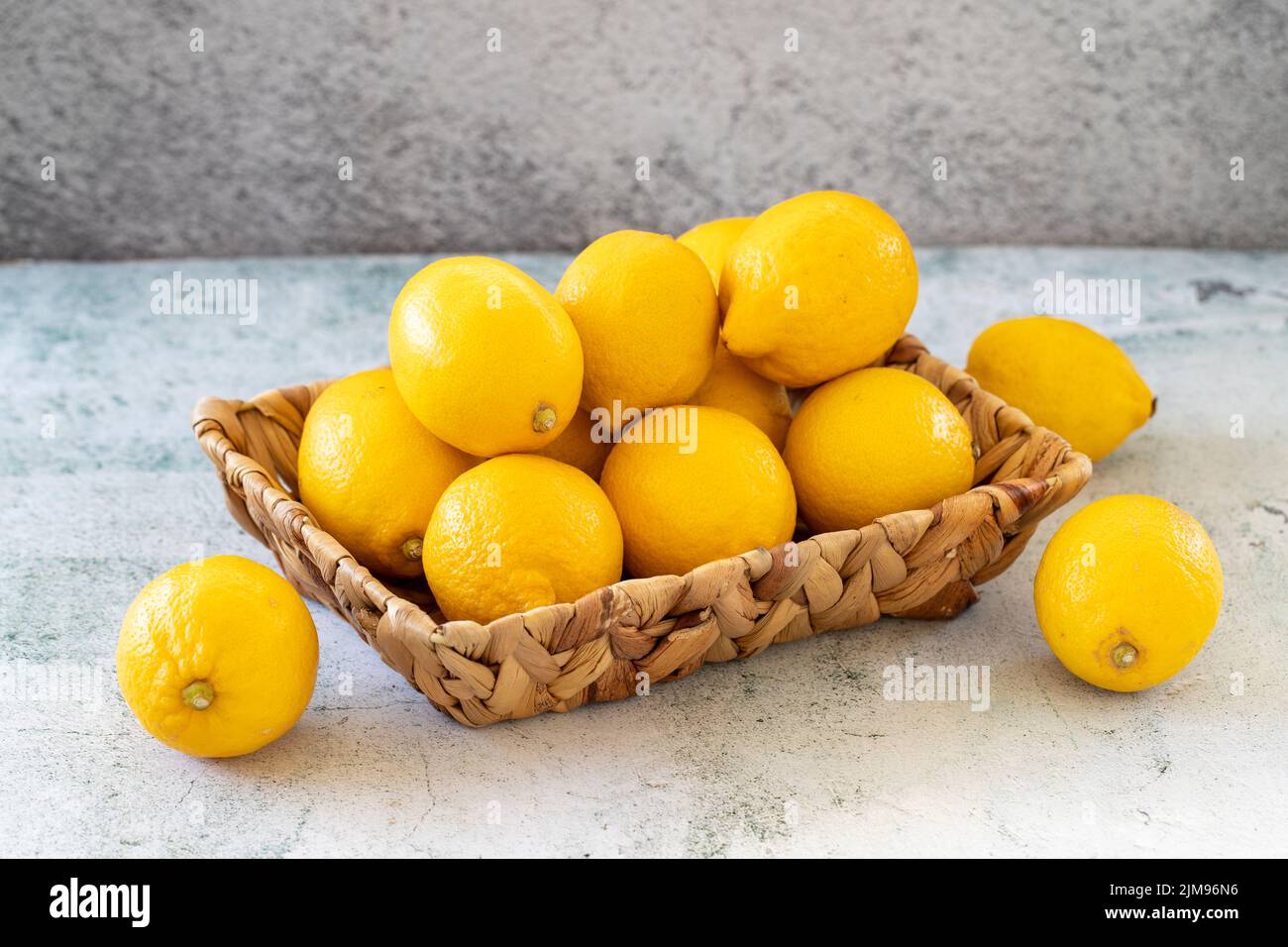 Fresh lemon. Organic lemons in a basket on a stone background. close up ...