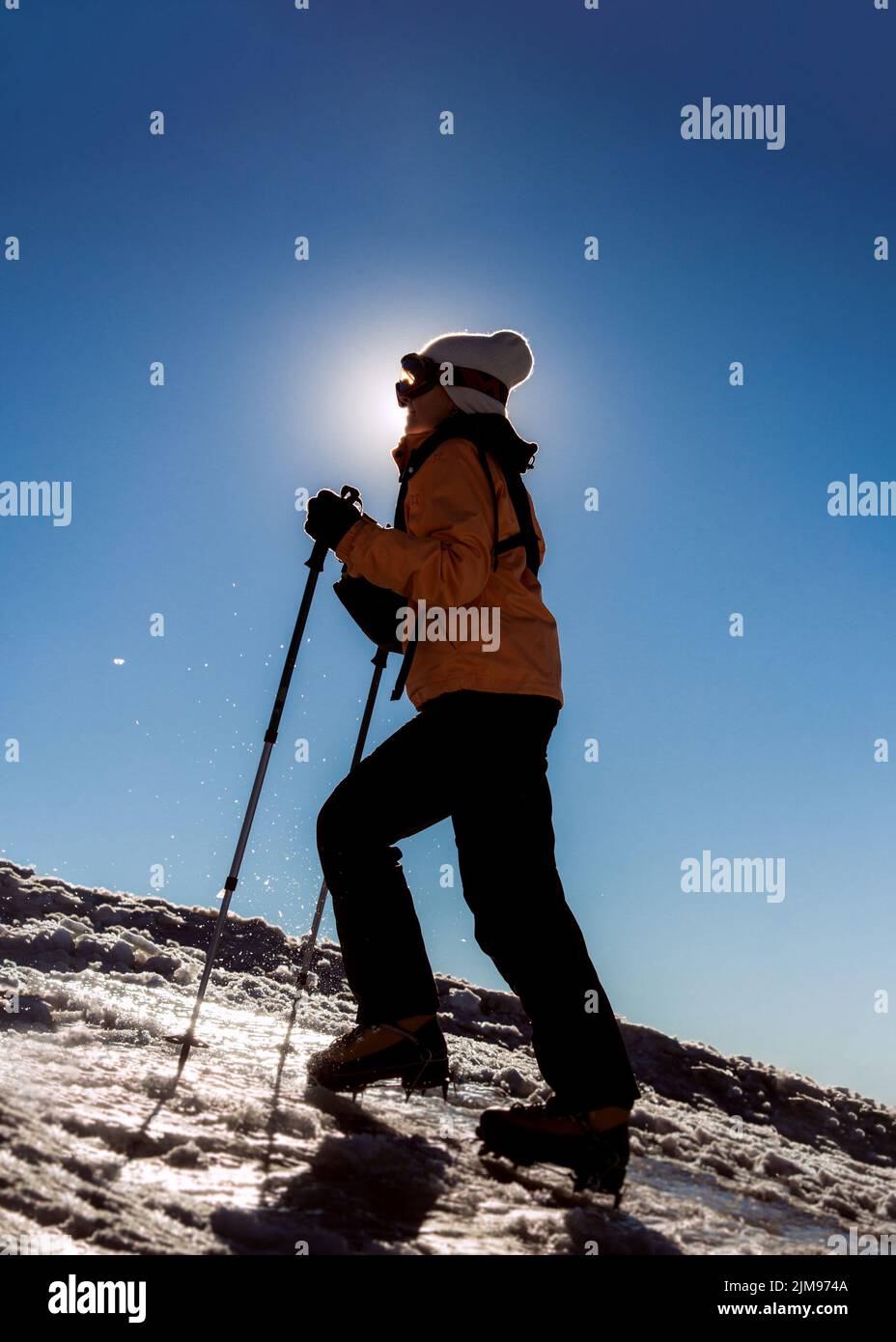 Happy mountaineer girl pounding boots in hard snow ascending up on the ...