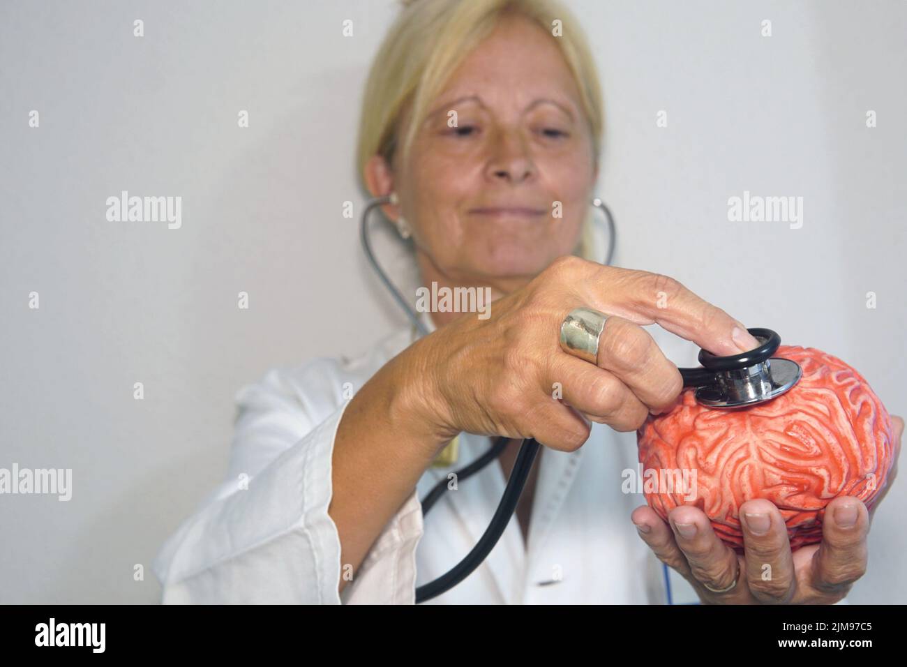 A doctor listens with a stethoscope to a rubber brain Stock Photo - Alamy