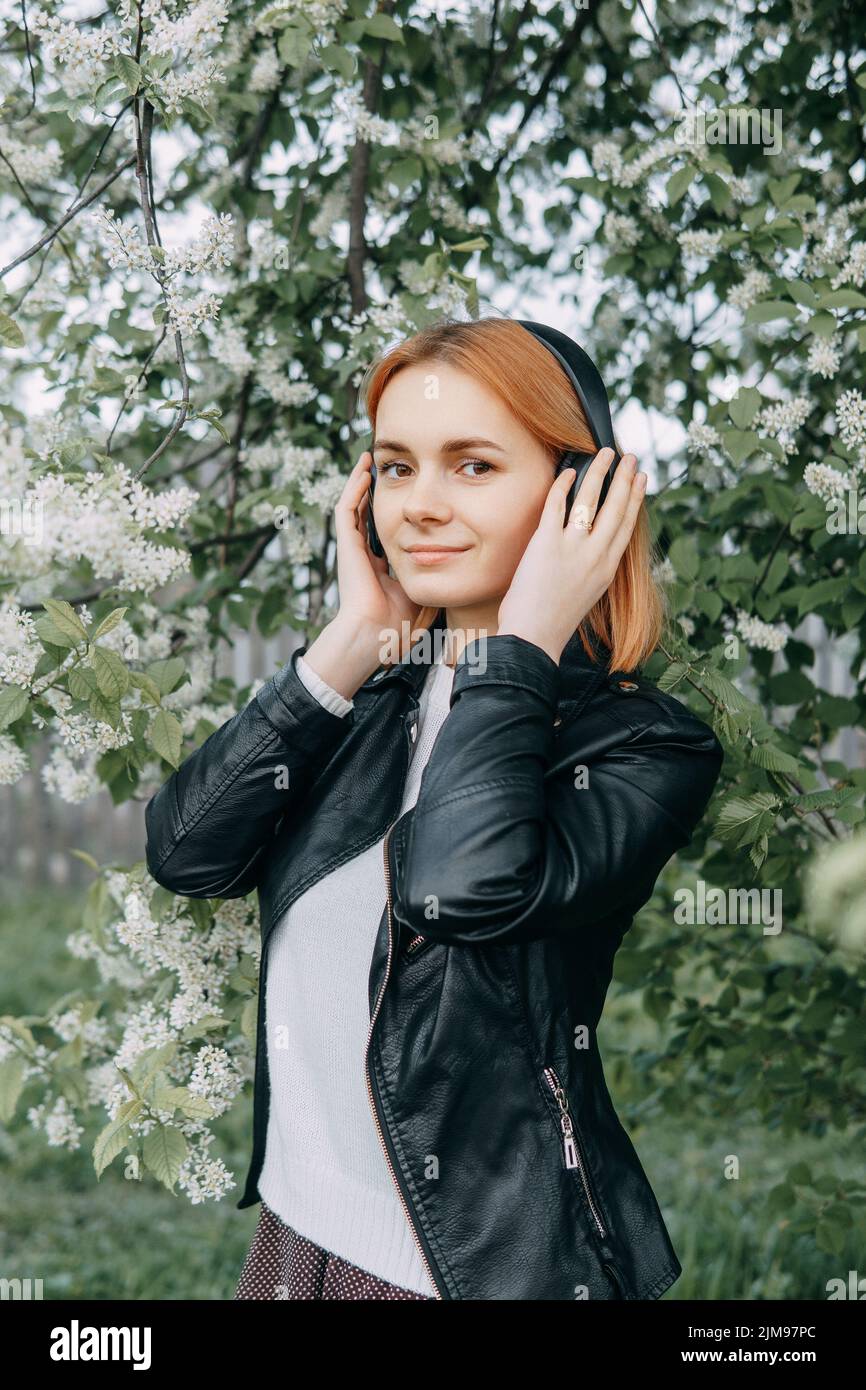 A red-haired teenage girl listens to music in headphones, configured ...