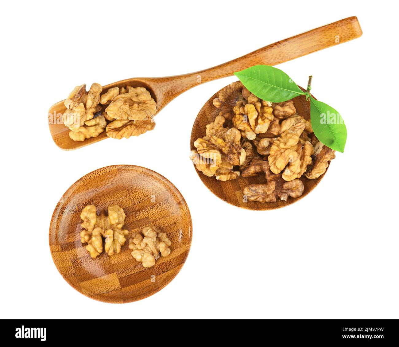 Handful of walnuts in wooden bowls, scoop and green leaves isolated ...