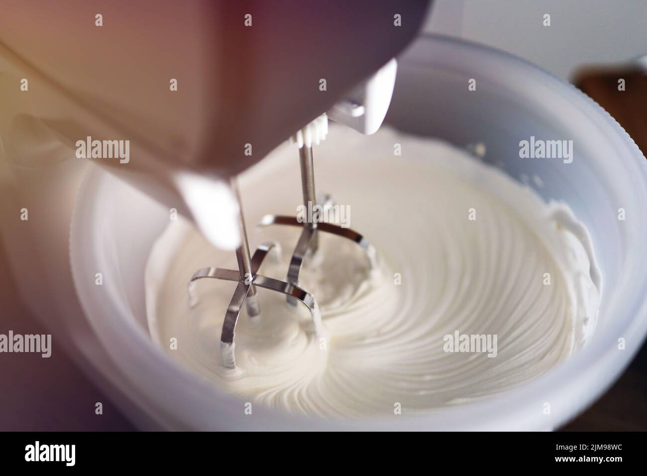 Mixing white egg cream in bowl with motor mixer. Baking cake. Whipped ...
