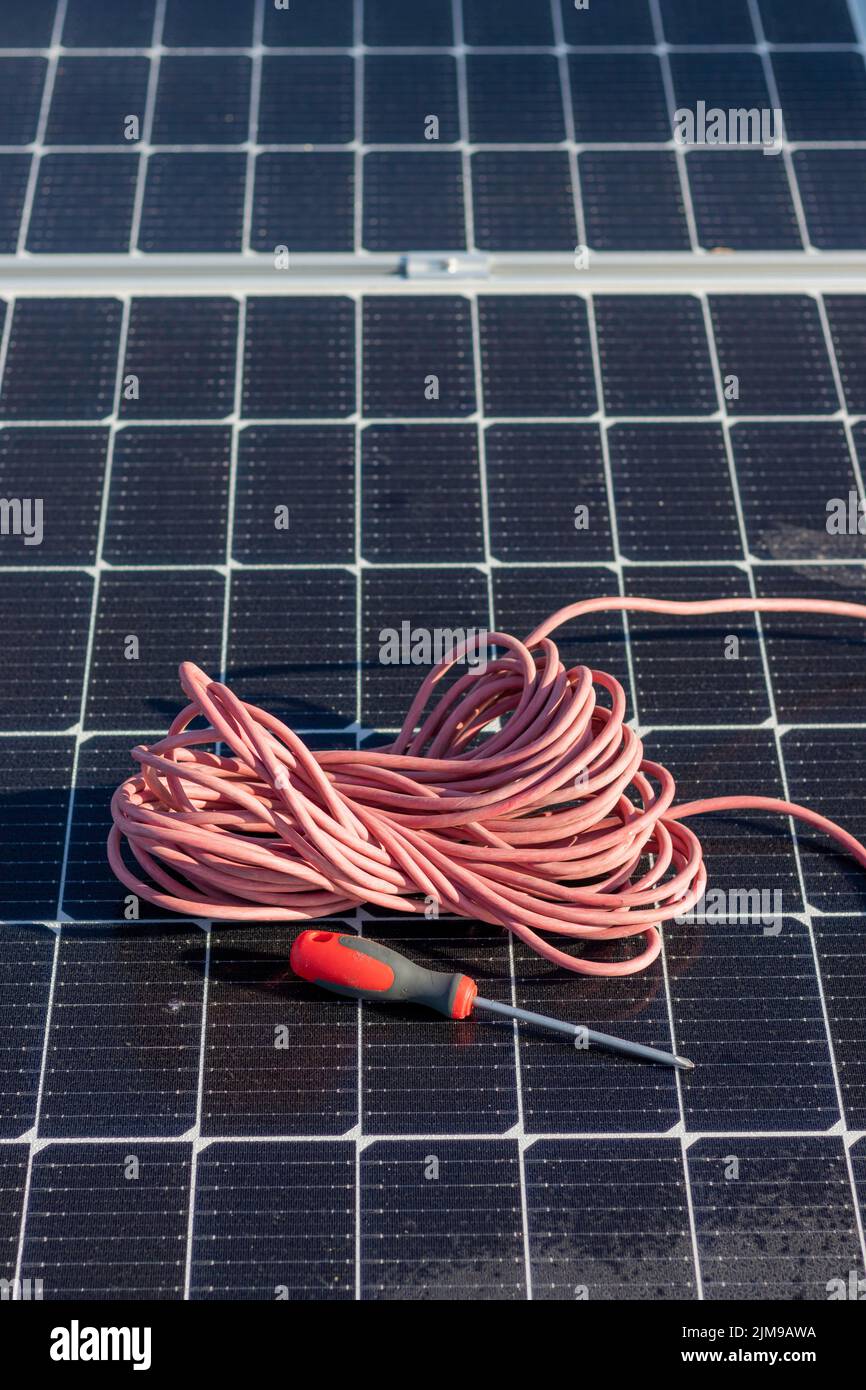 Vertical top view of red cable reel and a screwer leaning on a solar ...