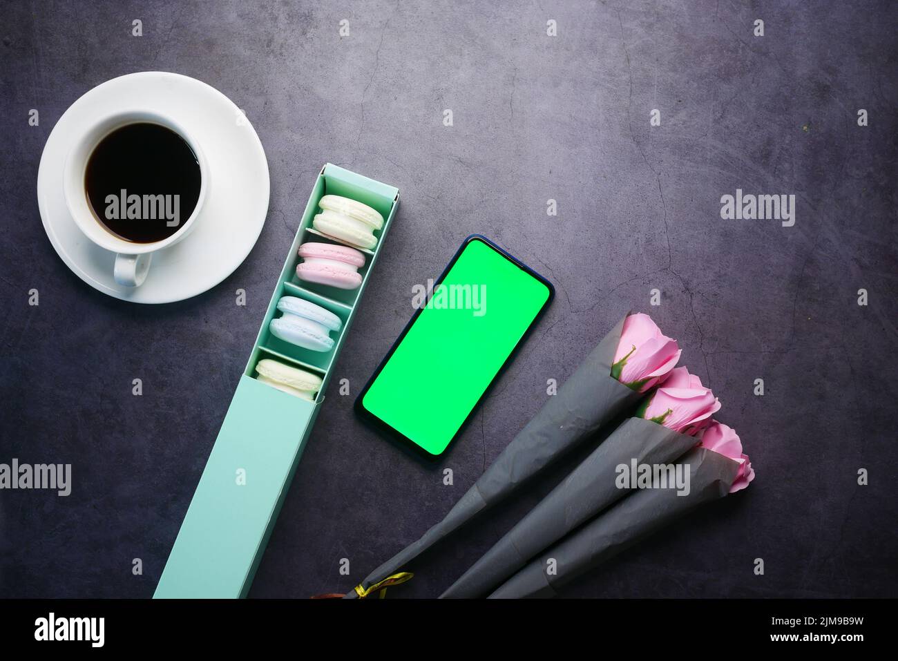 macaroon in a paper box, smart phone and tea up on black Stock Photo ...