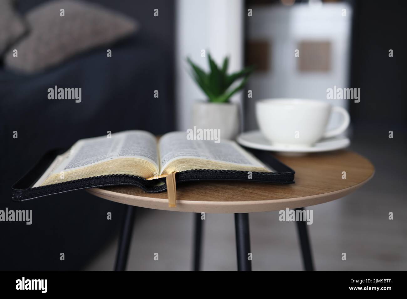 Open Bible with a cup of tea on a wooden table in the bedroom. Time for ...