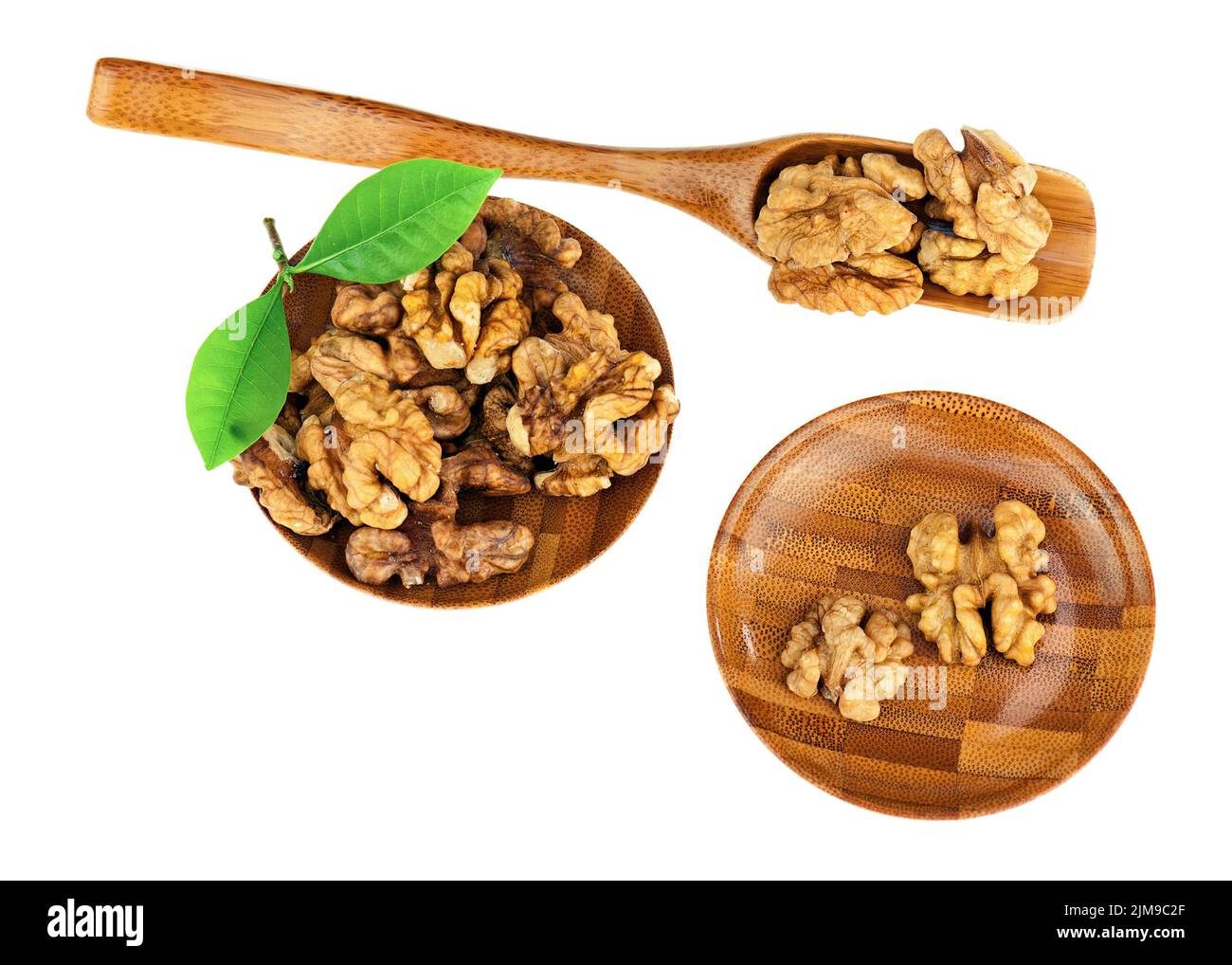 Handful of walnuts in wooden bowls, scoop and green leaves isolated ...