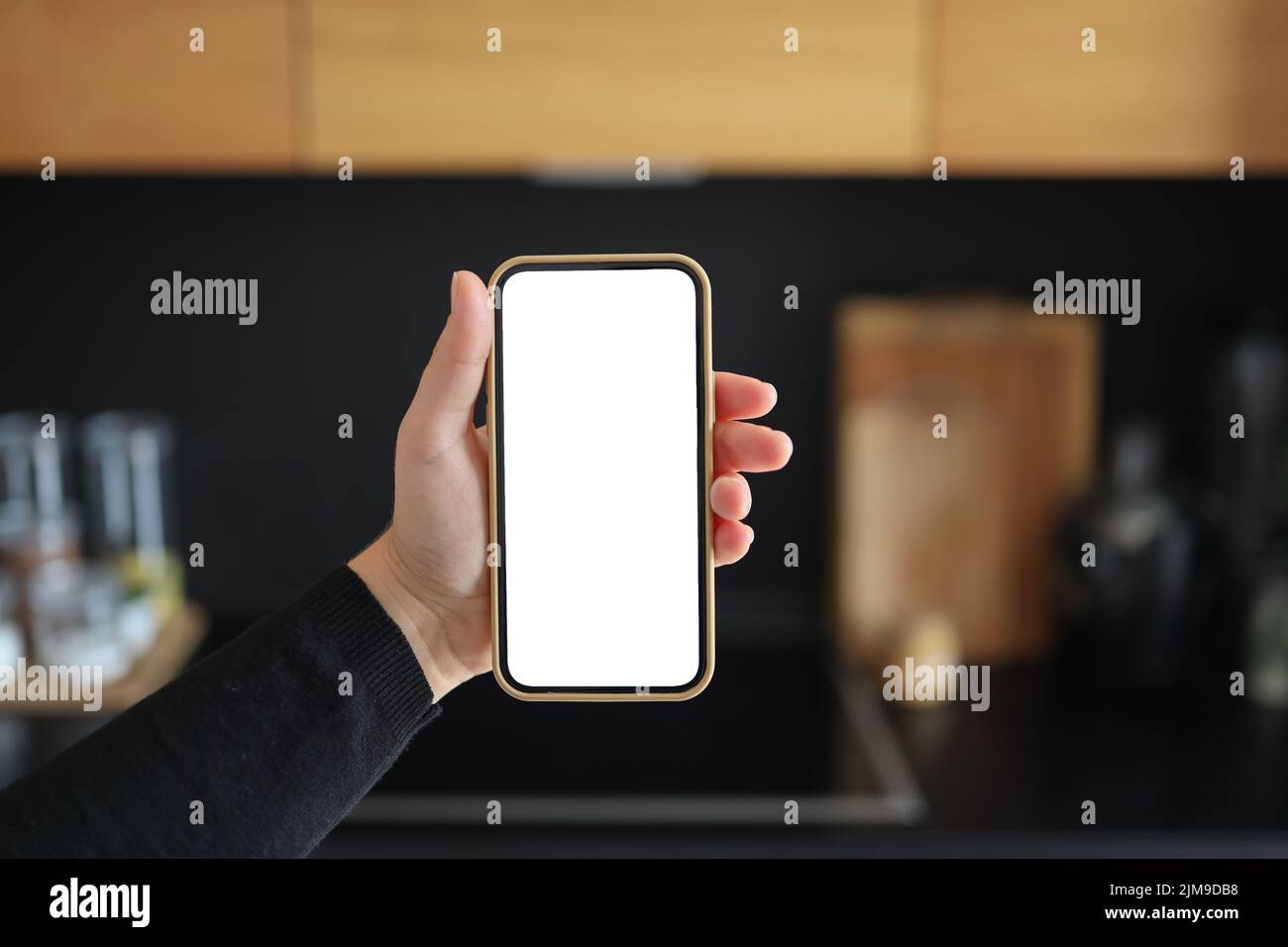 Woman hand holding smartphone with vertical white screen on kitchen at ...