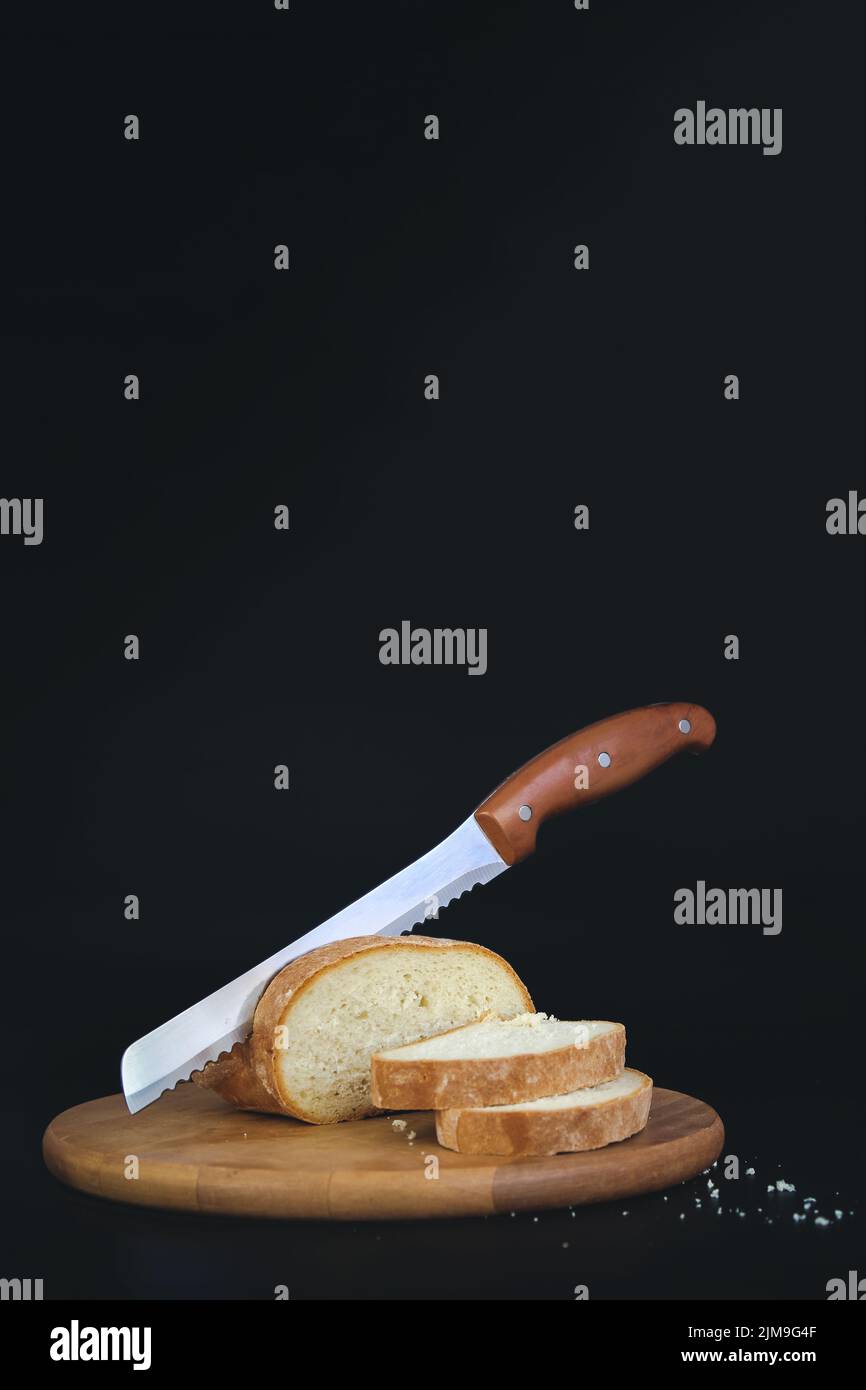 Large kitchen knife cuts freshly baked, fragrant, crisp rye bread, a ...