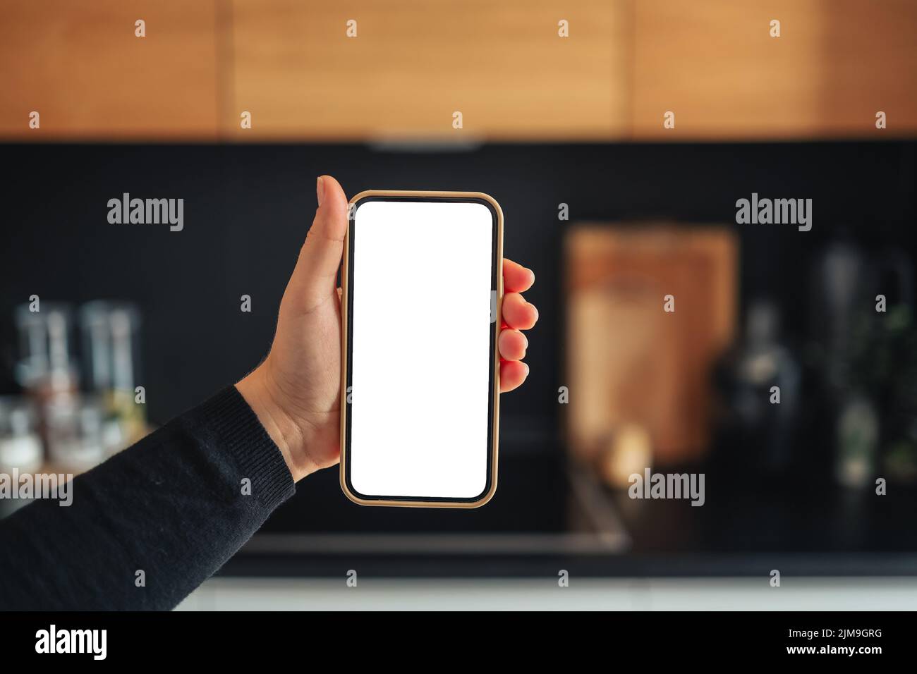 Woman hand holding smartphone with vertical white screen on kitchen at ...