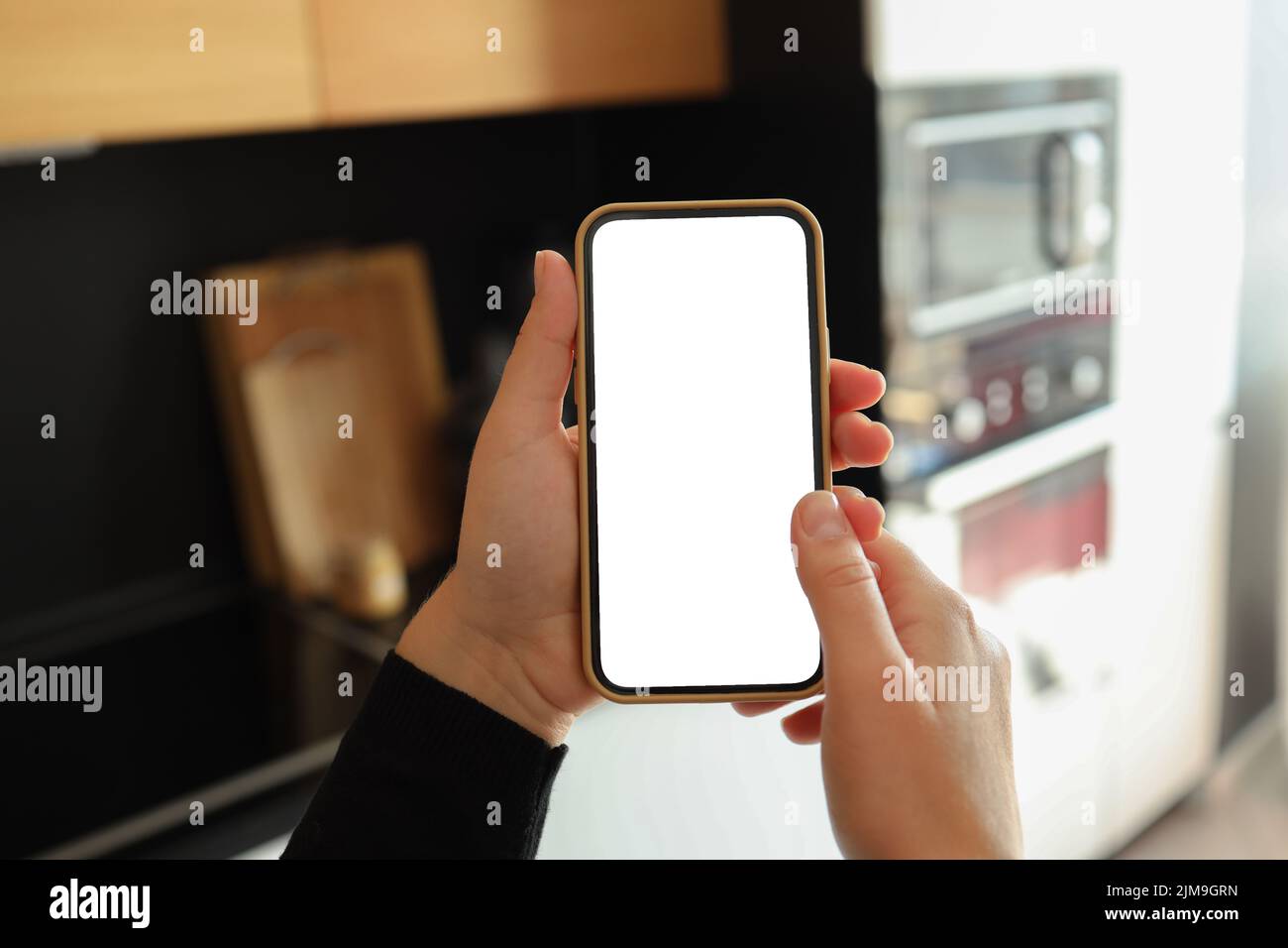 Woman hand holding smartphone with vertical white screen on kitchen at ...