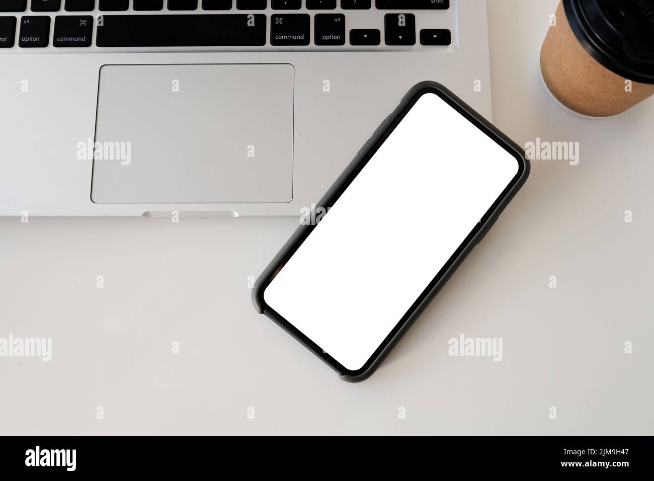 Close up smart phone and computer on white table top view. White screen ...